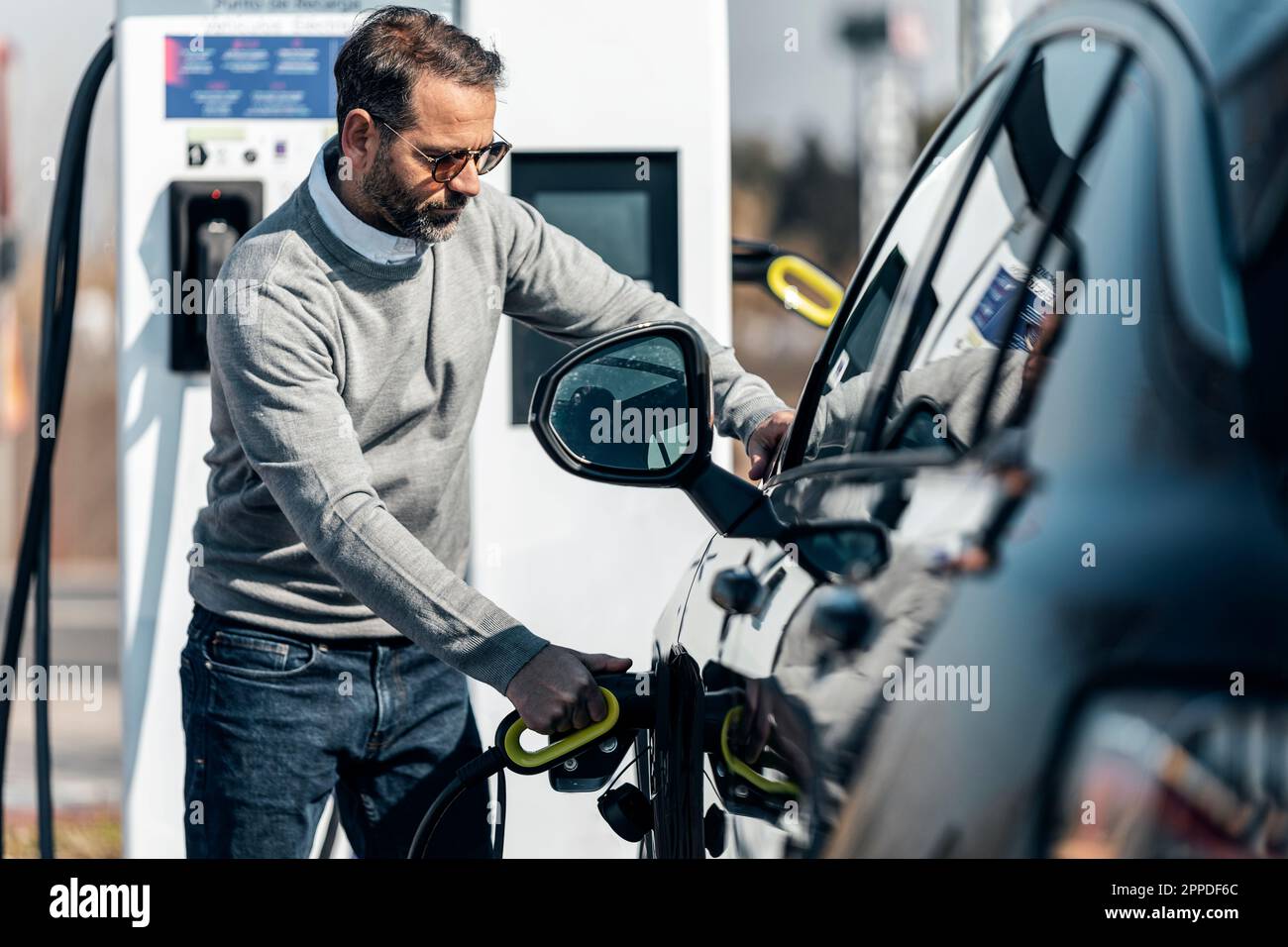 Man charging electric car standing at station Stock Photo - Alamy