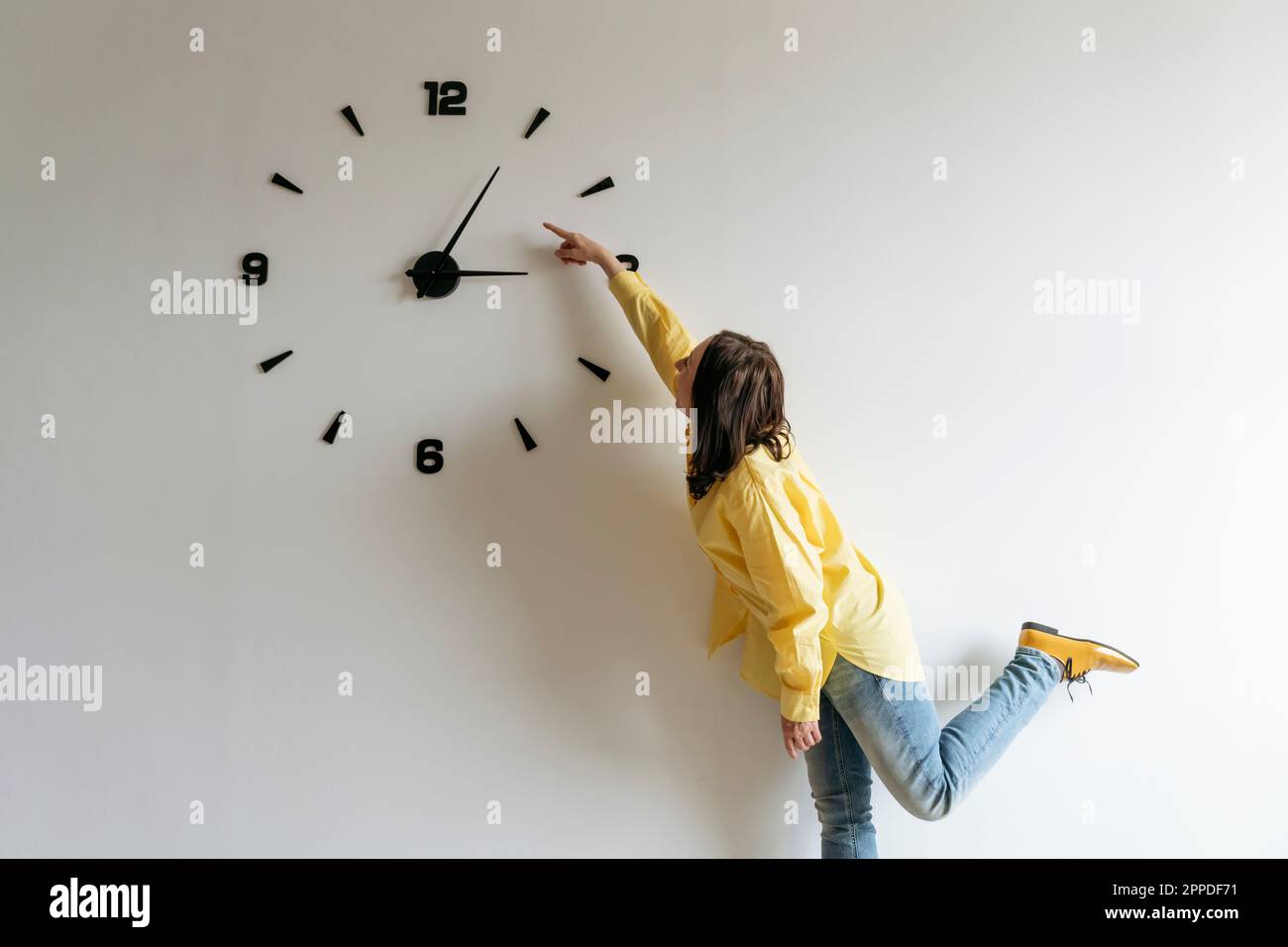 Woman pointing finger on large clock Stock Photo - Alamy