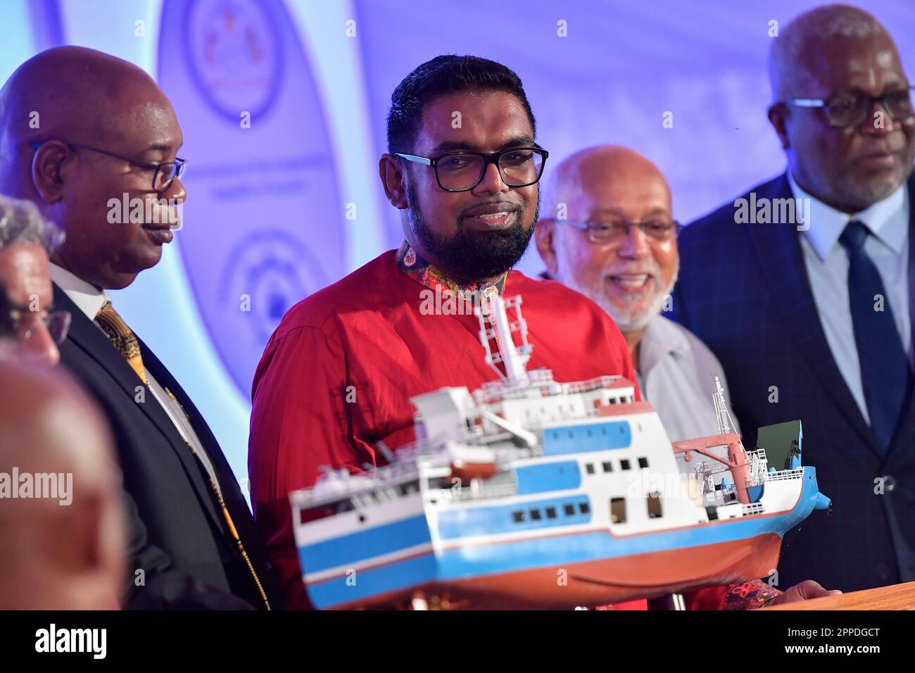 Guyana's President Mohamed Irfaan Ali, center, poses with a model of a ...