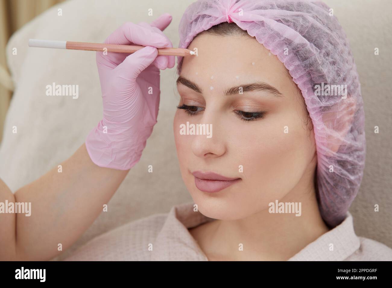 Cosmetologist drawing with white pencil on patient face. Cosmetologist ...