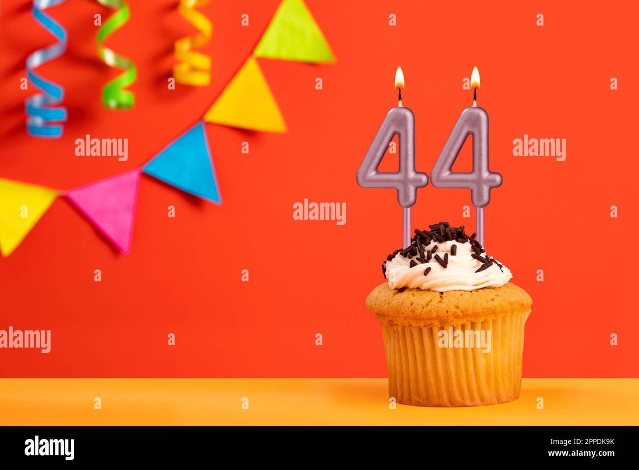 Birthday cake with number 44 candle - Sparkling orange background with ...