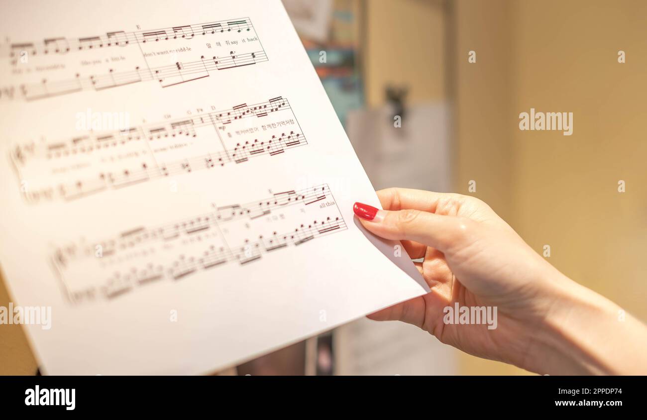 The female hand of a musician or composer hand writes a song or a ...