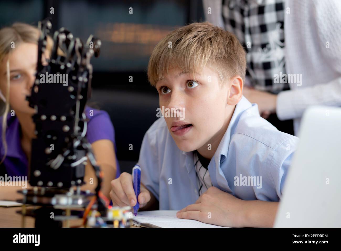 Caucasian two teenager students learning robotic arm in classroom ...