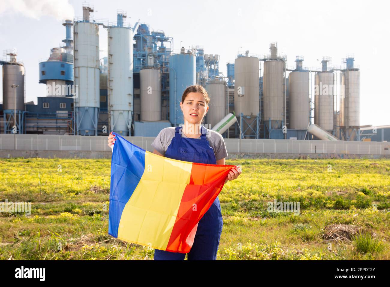 Sad young woman near factory with Romanian flag Stock Photo - Alamy