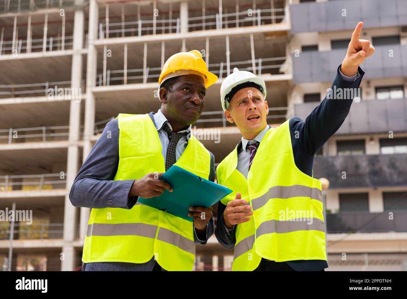 Young civil engineer discussing a construction plan with a colleague ...