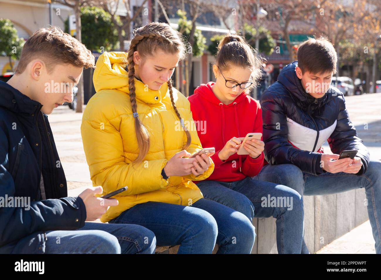 Four teenagers enthusiastically look at the screens of their ...
