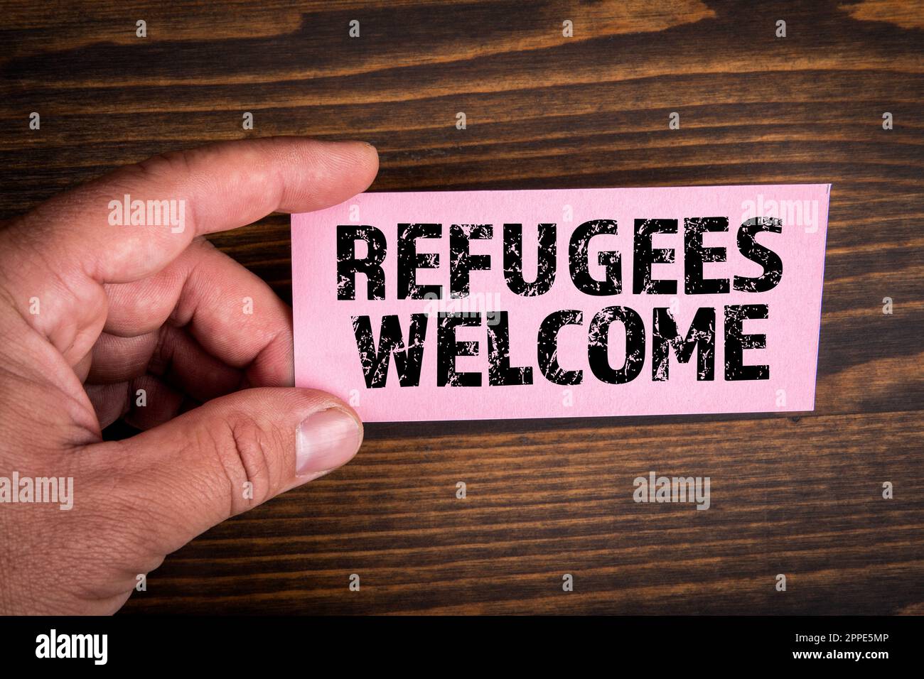 Refugees Welcome. Text on pink paper. Wood texture background Stock ...
