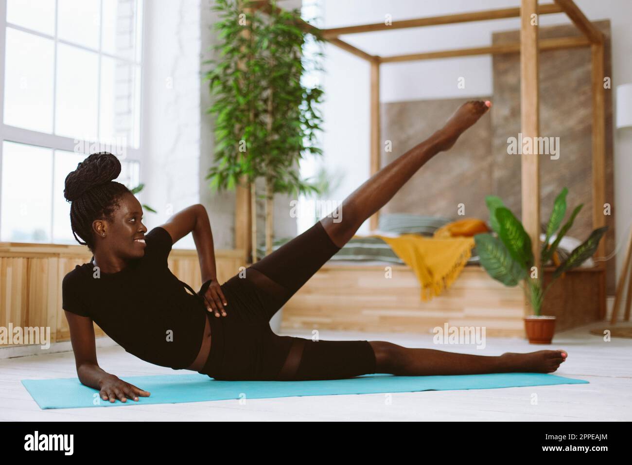 Beautiful athletic afro american woman lying on side and raising leg up ...
