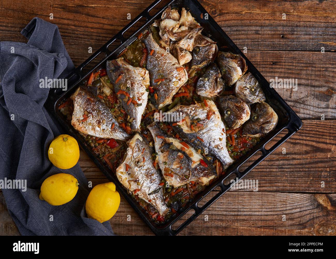Delicious oven cooked bream in a metal tray on rustic wooden board ...
