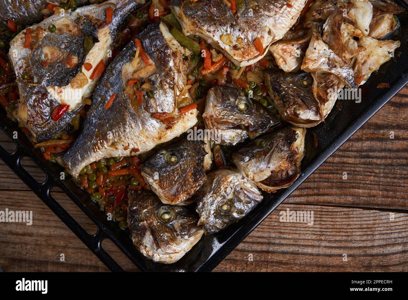 Delicious oven cooked bream in a metal tray on rustic wooden board ...