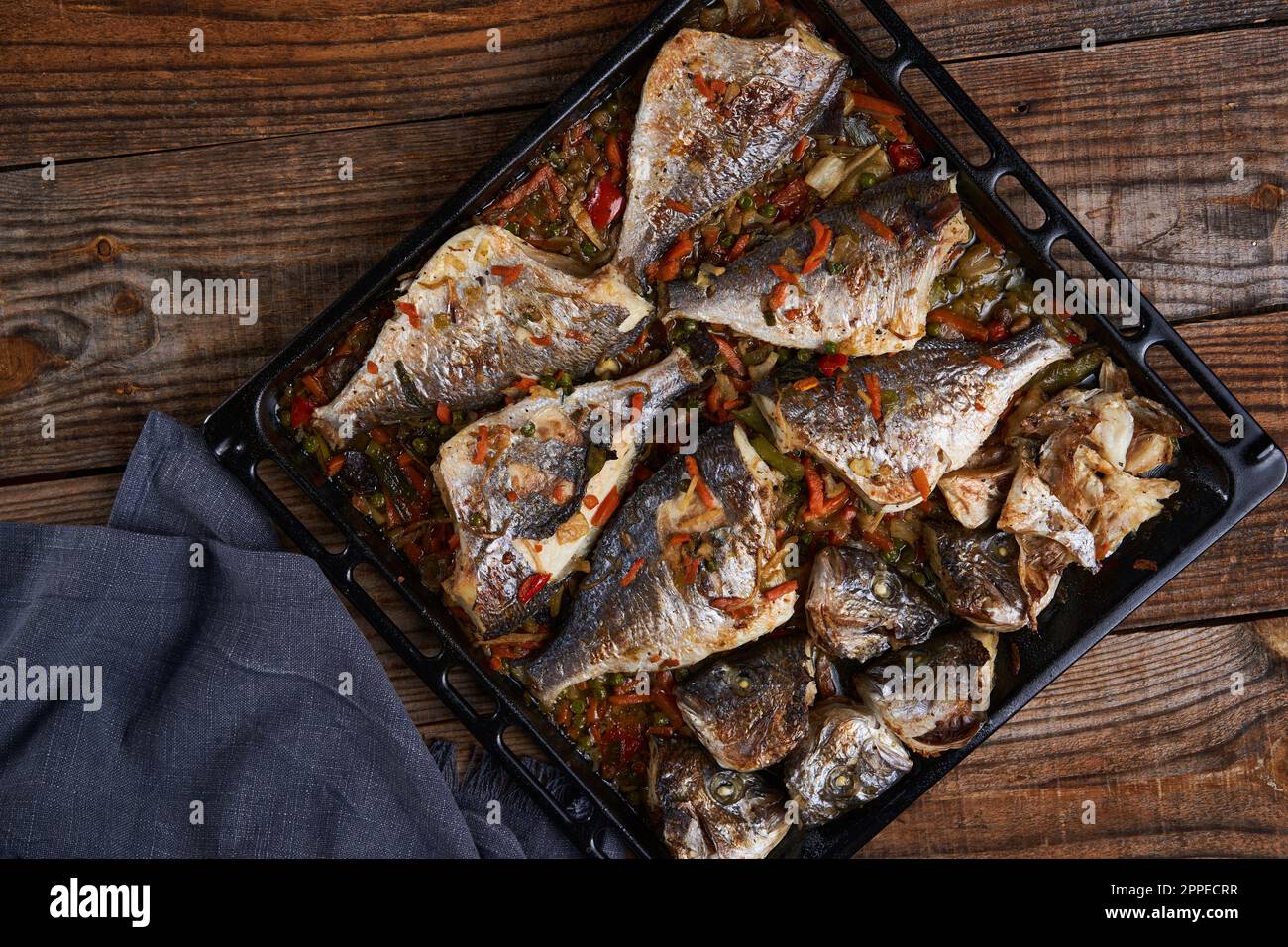 Delicious oven cooked bream in a metal tray on rustic wooden board ...
