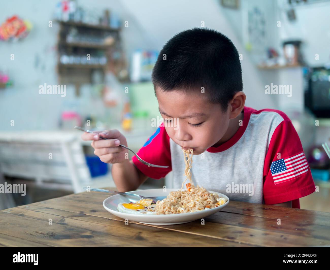Happy Asian boy eating delicious noodle Stock Photo - Alamy