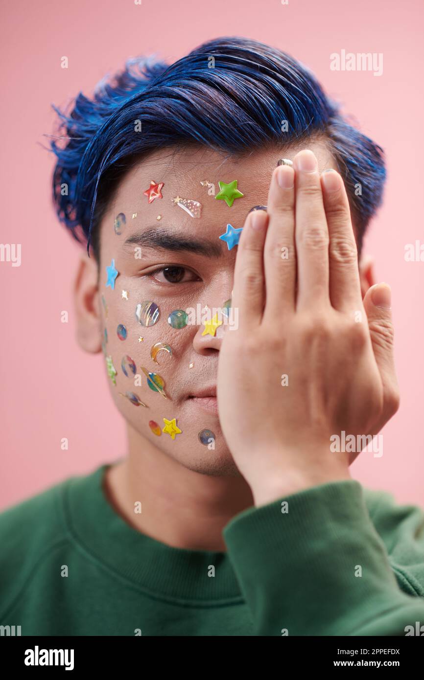 Young man with stickers on face covering half of face with hand Stock ...