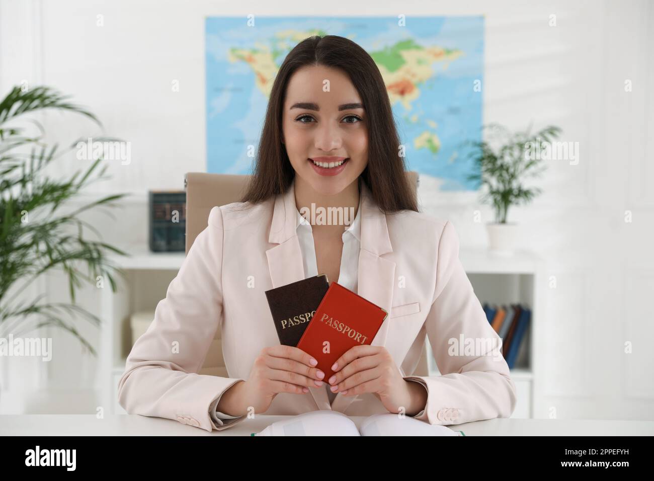 Happy manager holding passports at desk in travel agency Stock Photo ...