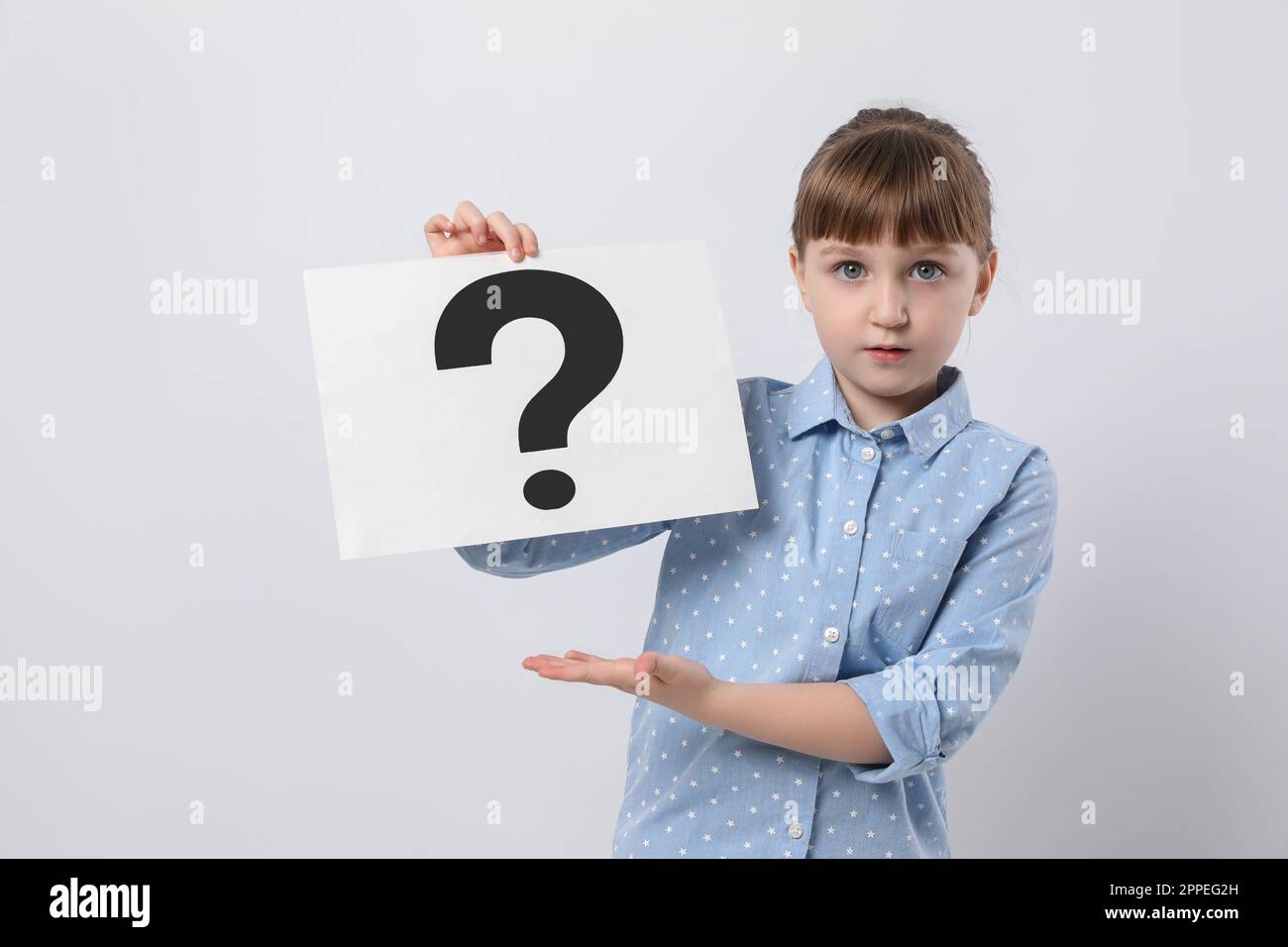 Emotional girl holding sheet of paper with question mark on white ...