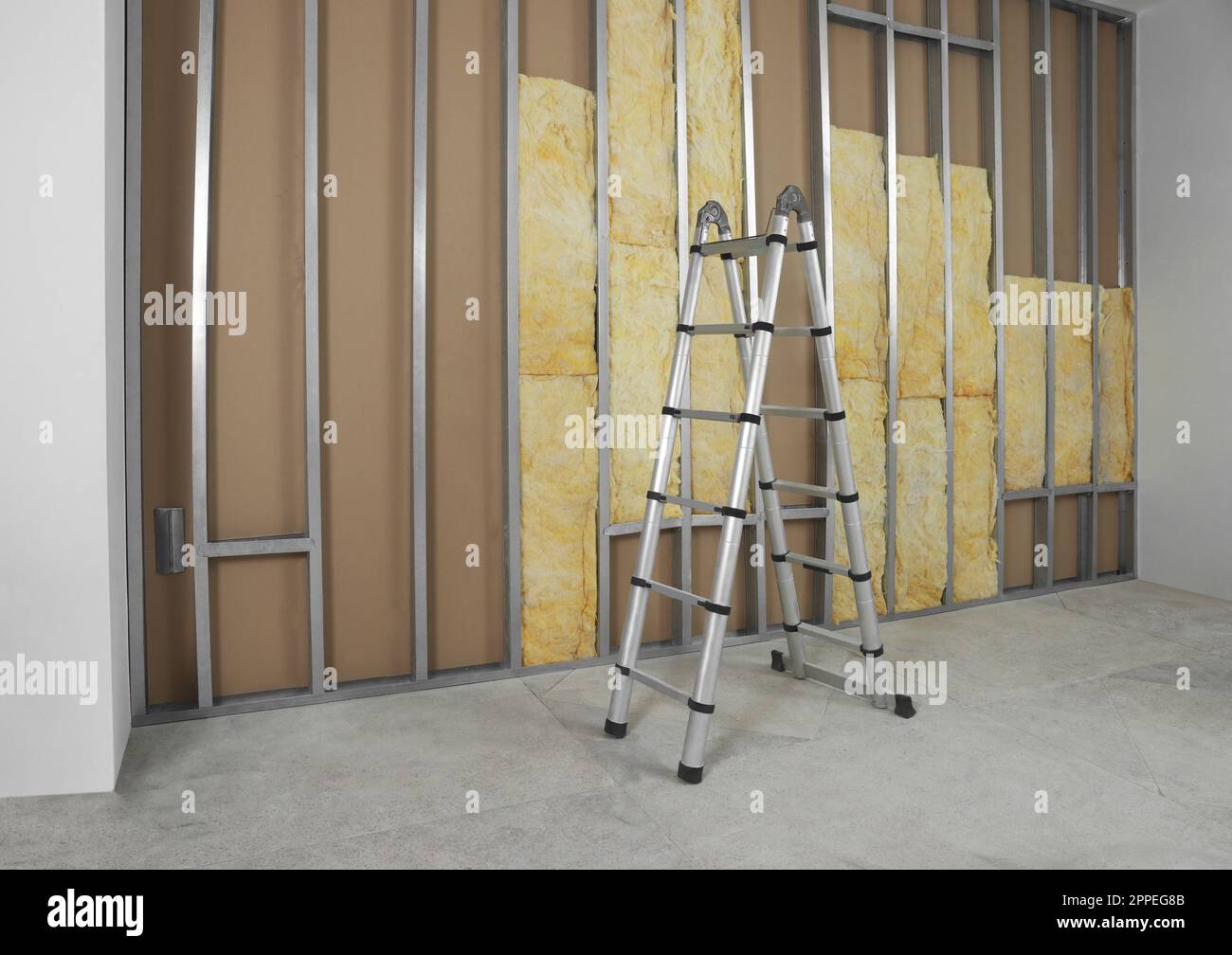 Ladder near wall with metal studs and insulation material indoors Stock ...