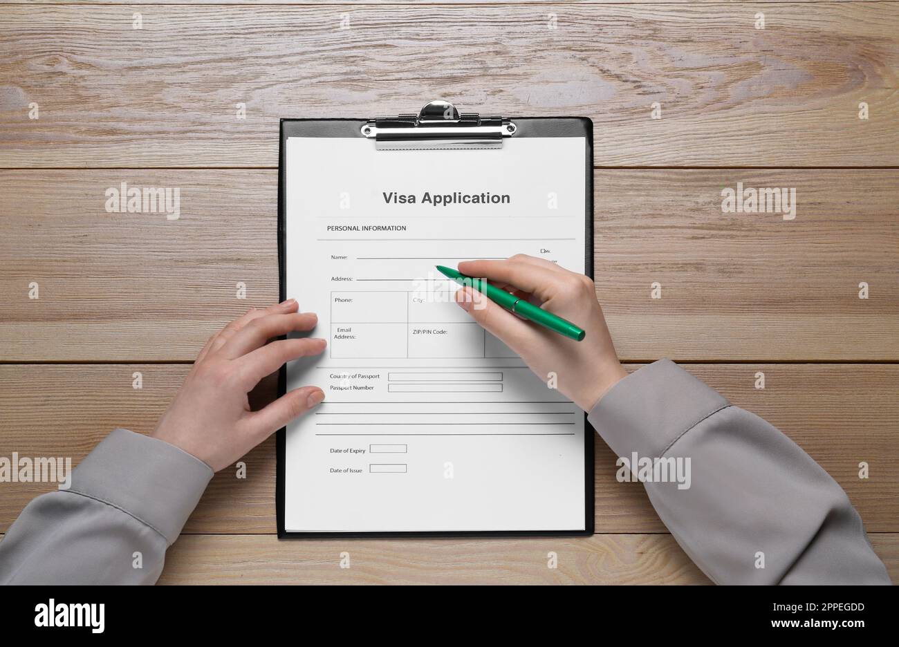 Woman filling visa application form at wooden table, top view Stock ...