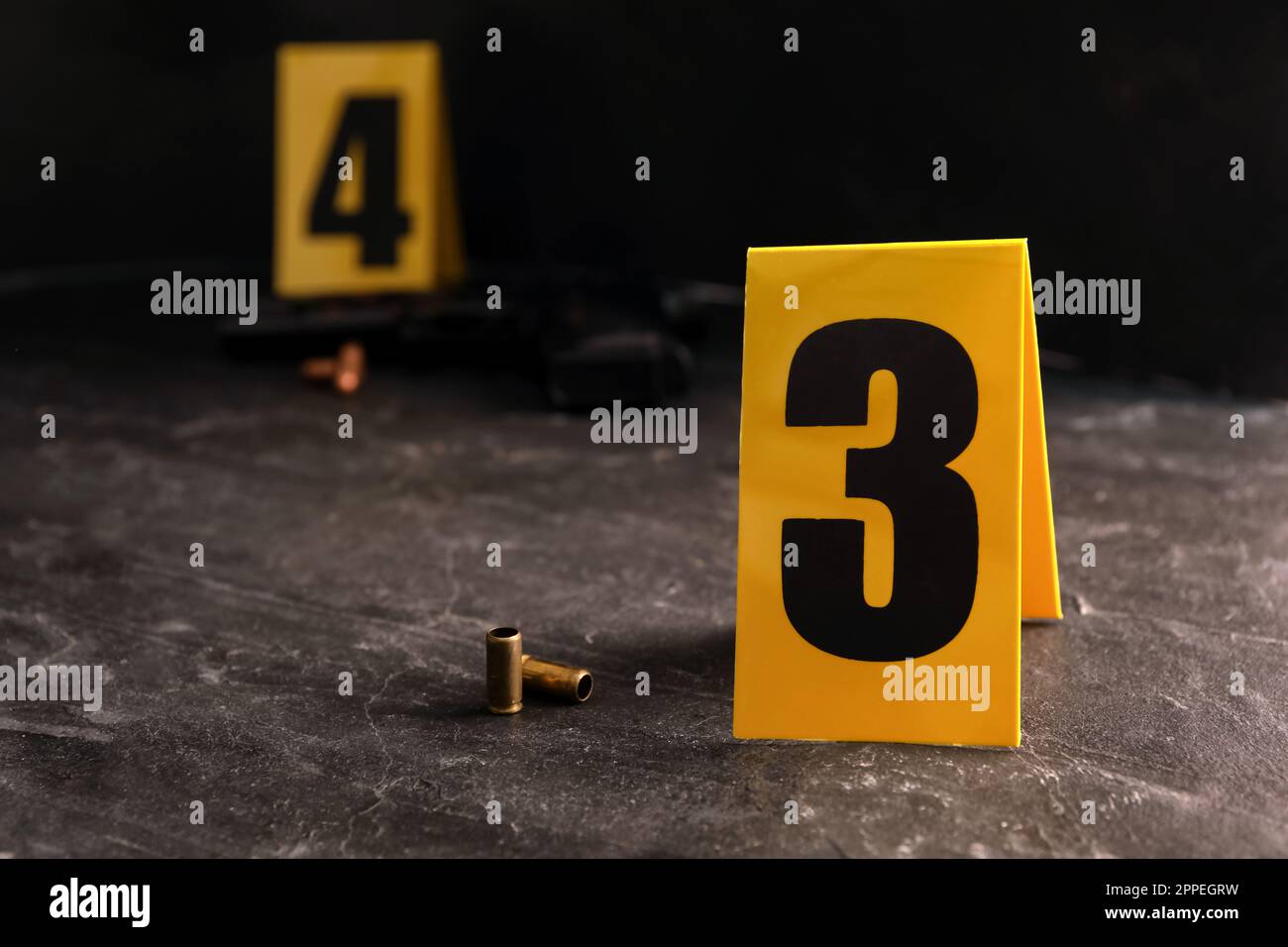 Shell casings and evidence marker on black slate table, closeup. Crime ...