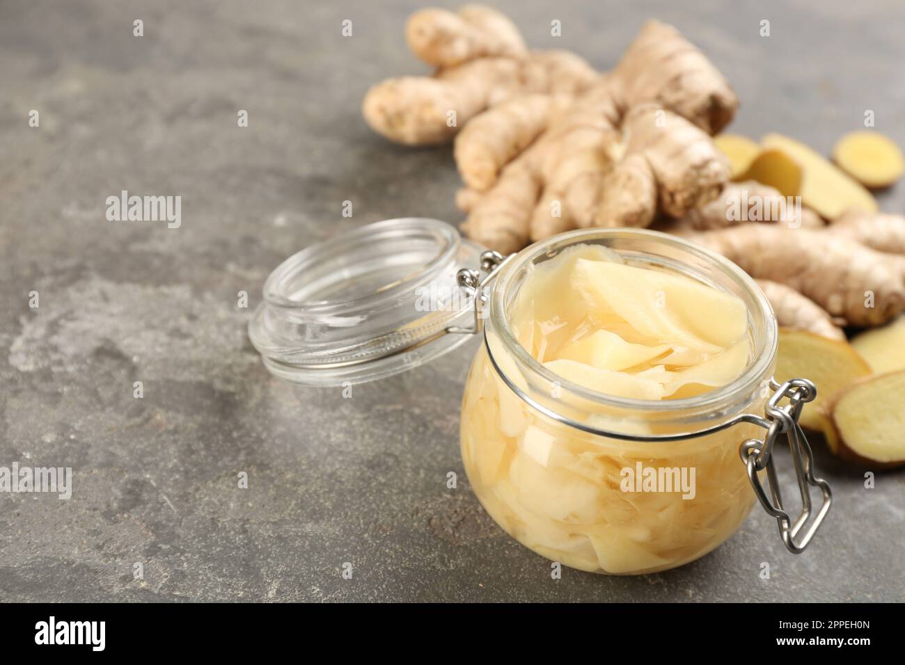 Spicy pickled ginger and root on light grey table, closeup. Space for ...