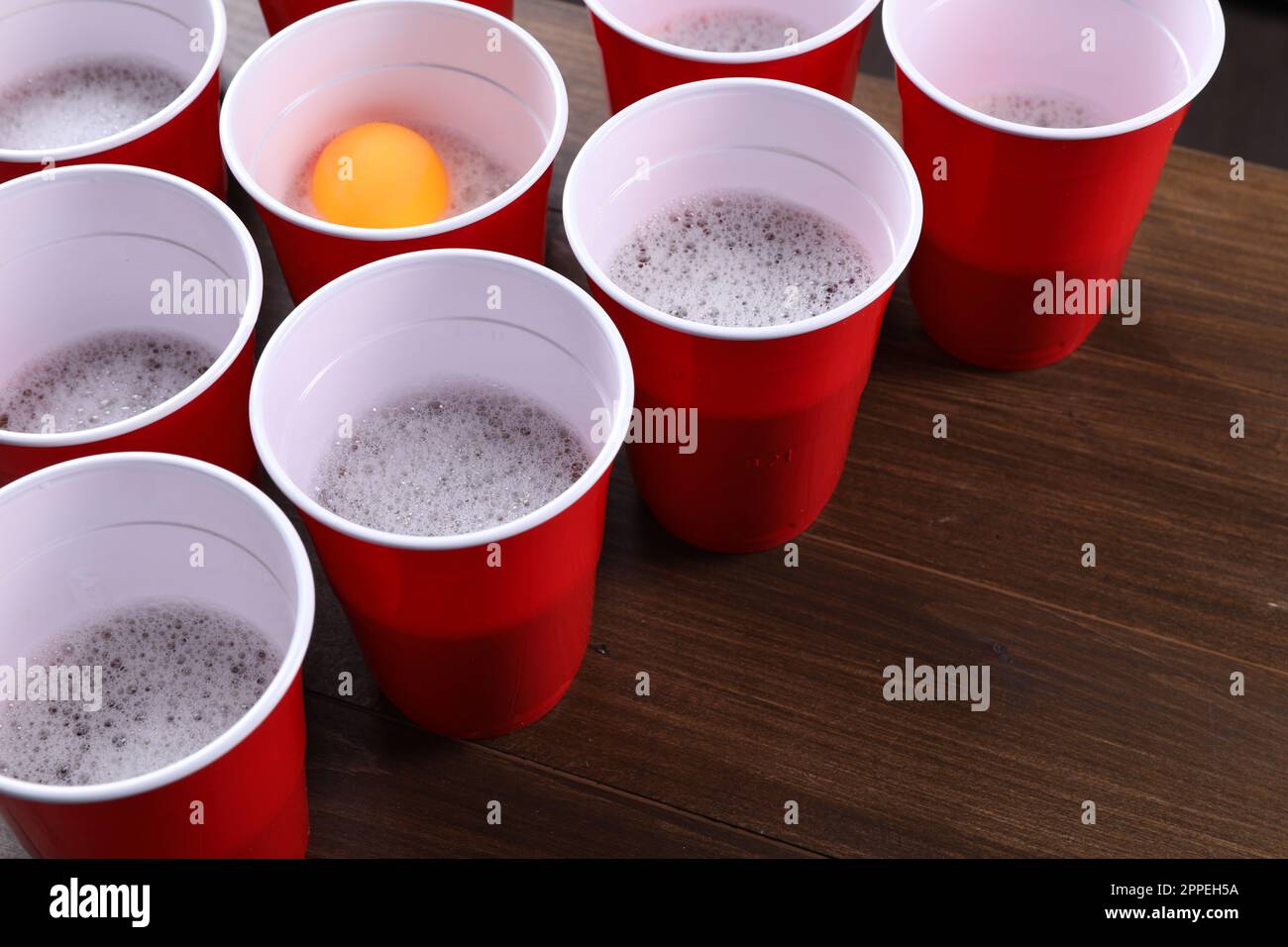Plastic cups and ball on wooden table, space for text. Beer pong game ...