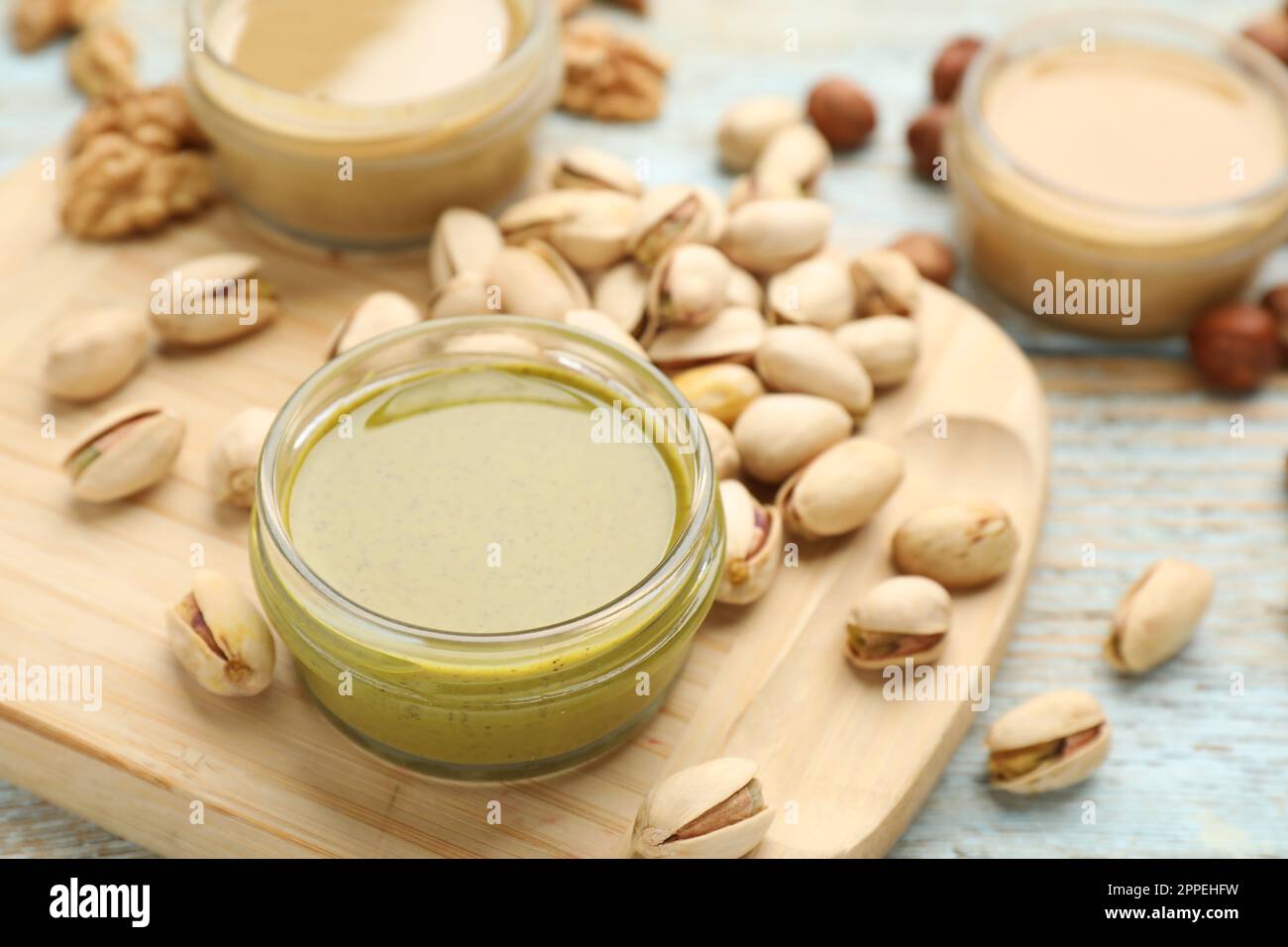 Different types of delicious nut butters and ingredients on light blue ...