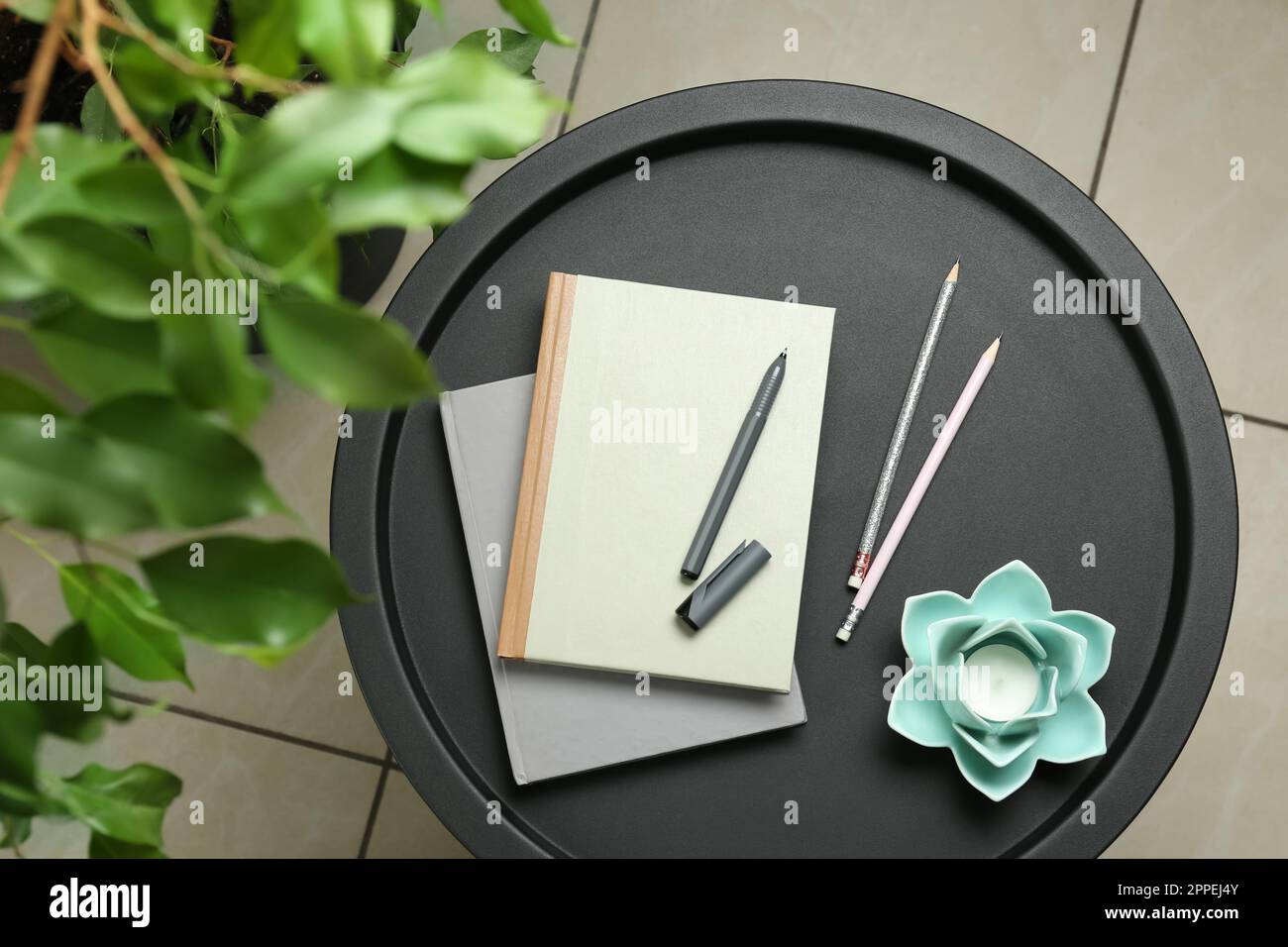 Notebooks, pen, pencils and decor on round table indoors, top view ...