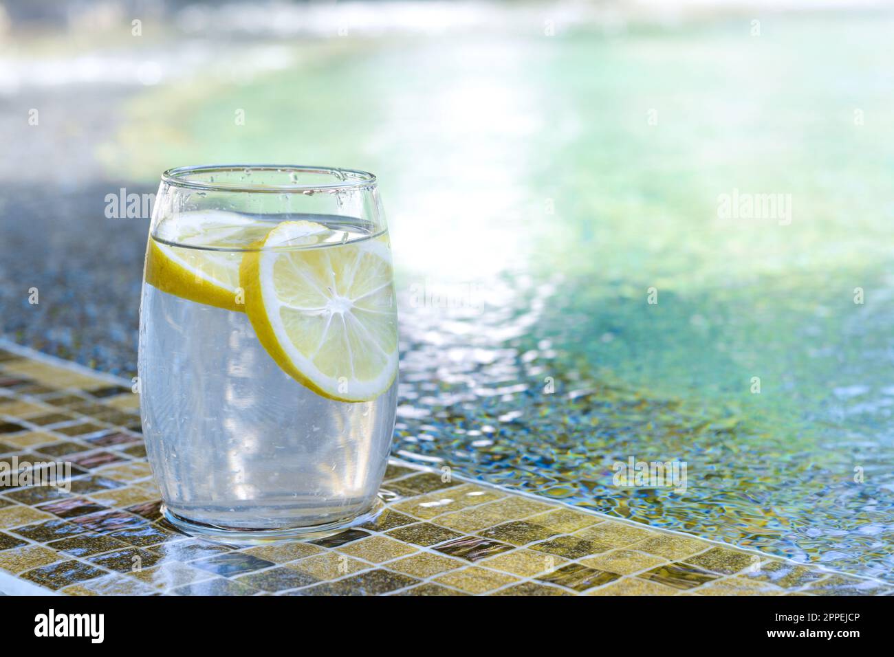 Refreshing water with lemon on edge of swimming pool, space for text ...