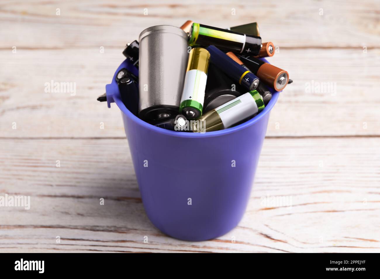 Used batteries in bucket on white wooden table Stock Photo - Alamy