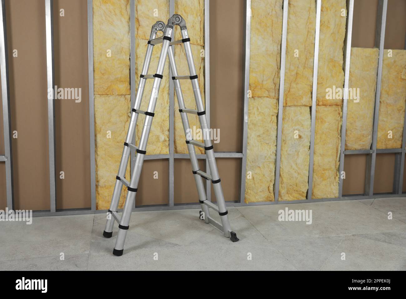 Ladder near wall with metal studs and insulation material indoors Stock ...