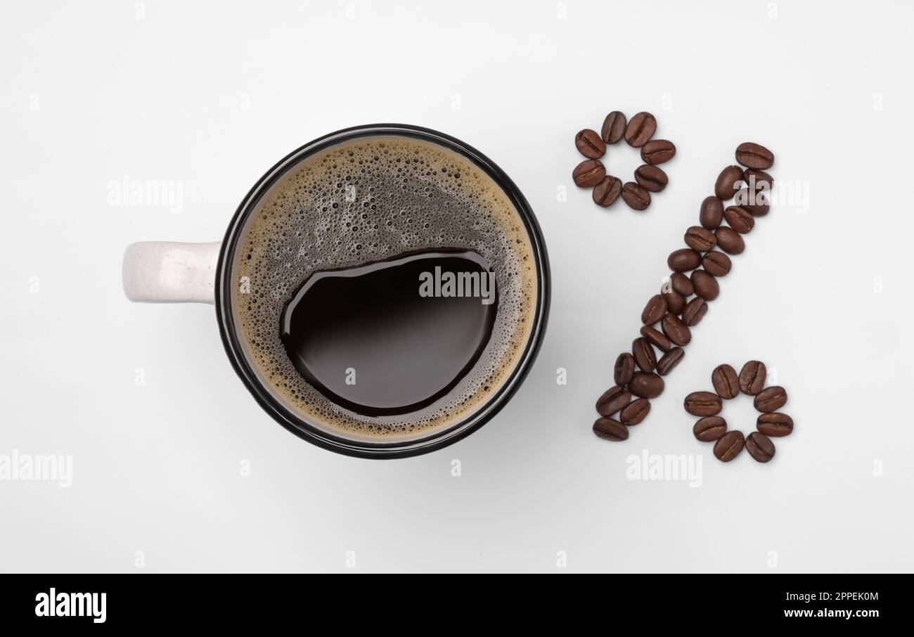 Cup of coffee and beans as percent sign on white background, top view ...