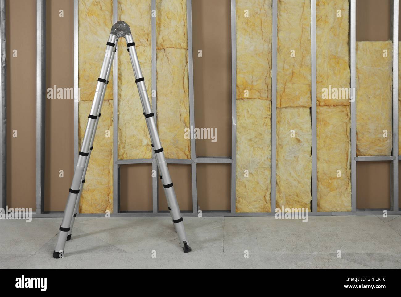 Ladder near wall with metal studs and insulation material indoors Stock ...