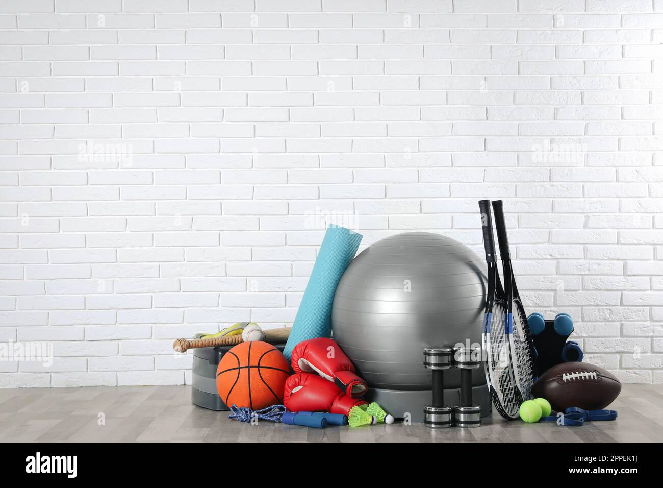 Set of different sports equipment on floor near white brick wall Stock ...