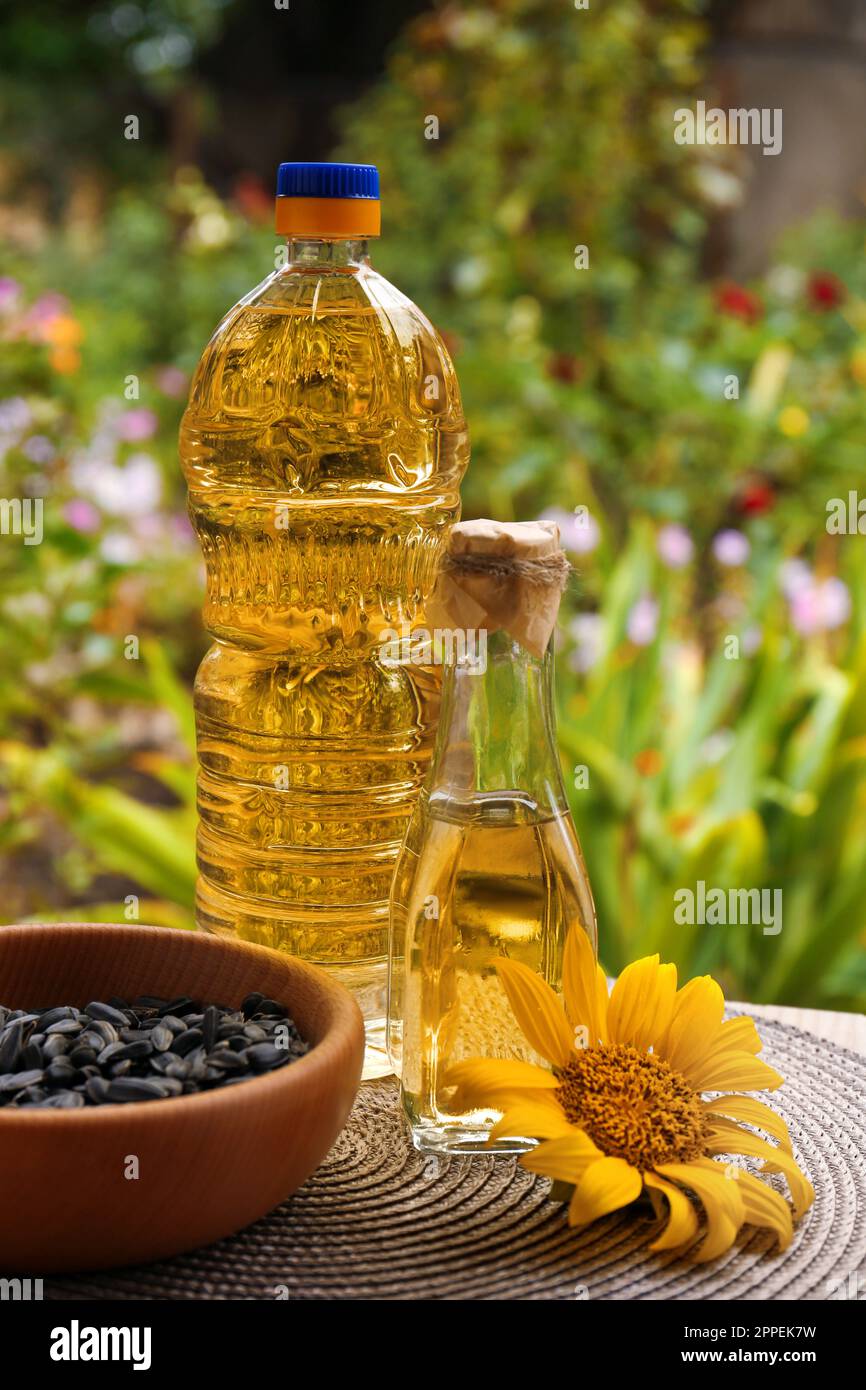 Bottles of sunflower oil and seeds in bowl on table outdoors Stock ...