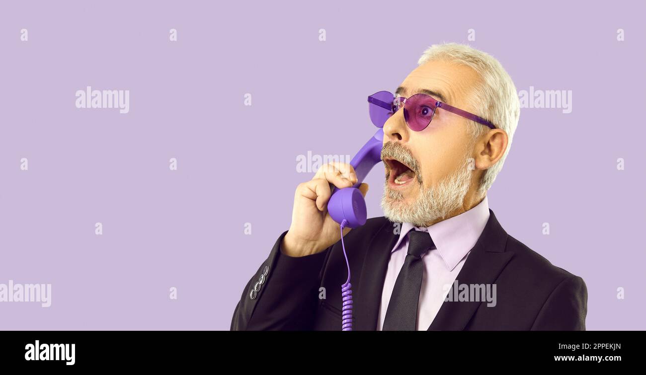 Senior man talking on landline phone with shocked and scared face ...