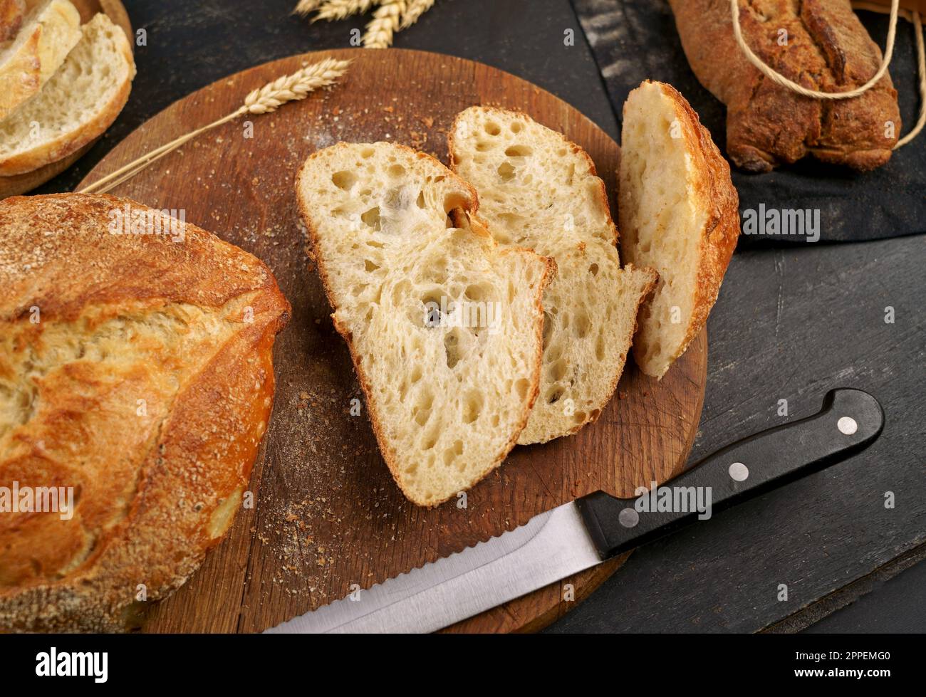 Round loaf of freshly baked sourdough bread with knife on cutting board ...