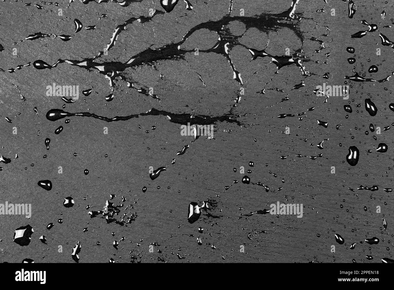 Water drops on dark flat stone surface of basalt or granite background ...