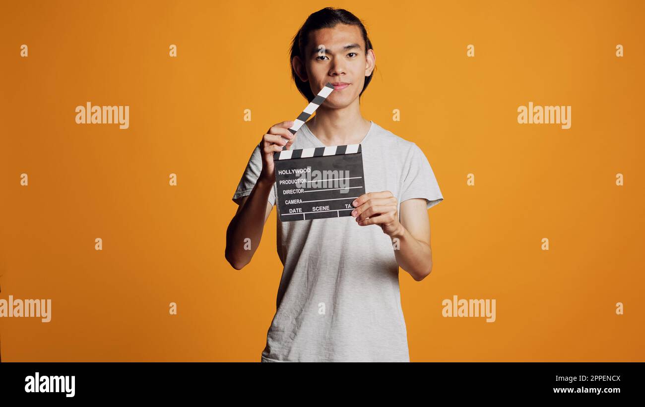 Casual modern man using film slate in studio, working in filming and ...