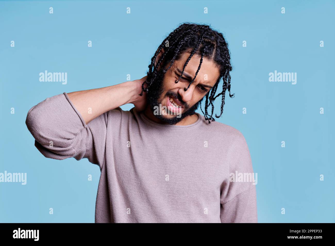 Arab man suffering from neck pain discomfort and massaging muscles with ...
