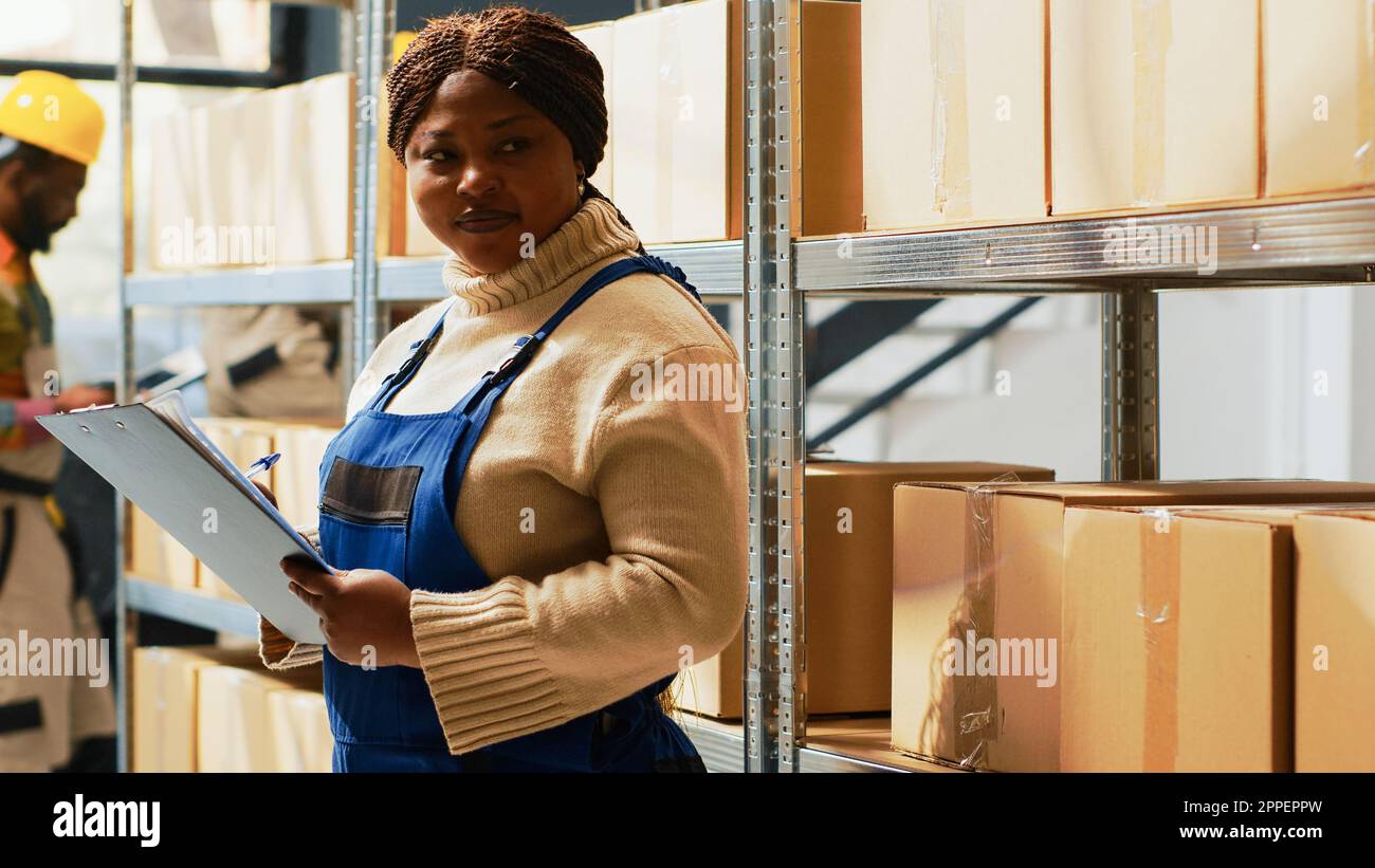 Young woman checking inventory list on clipboard, working with papers ...