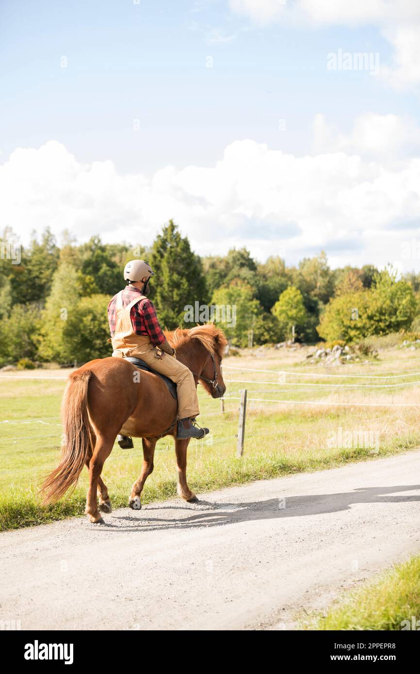 Male farmer riding horse on country road Stock Photo - Alamy