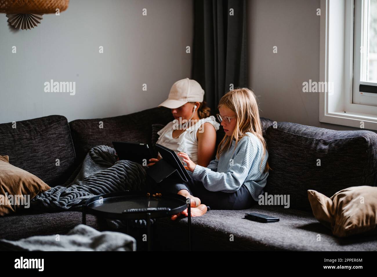 Girls on sofa using digital tablets Stock Photo - Alamy