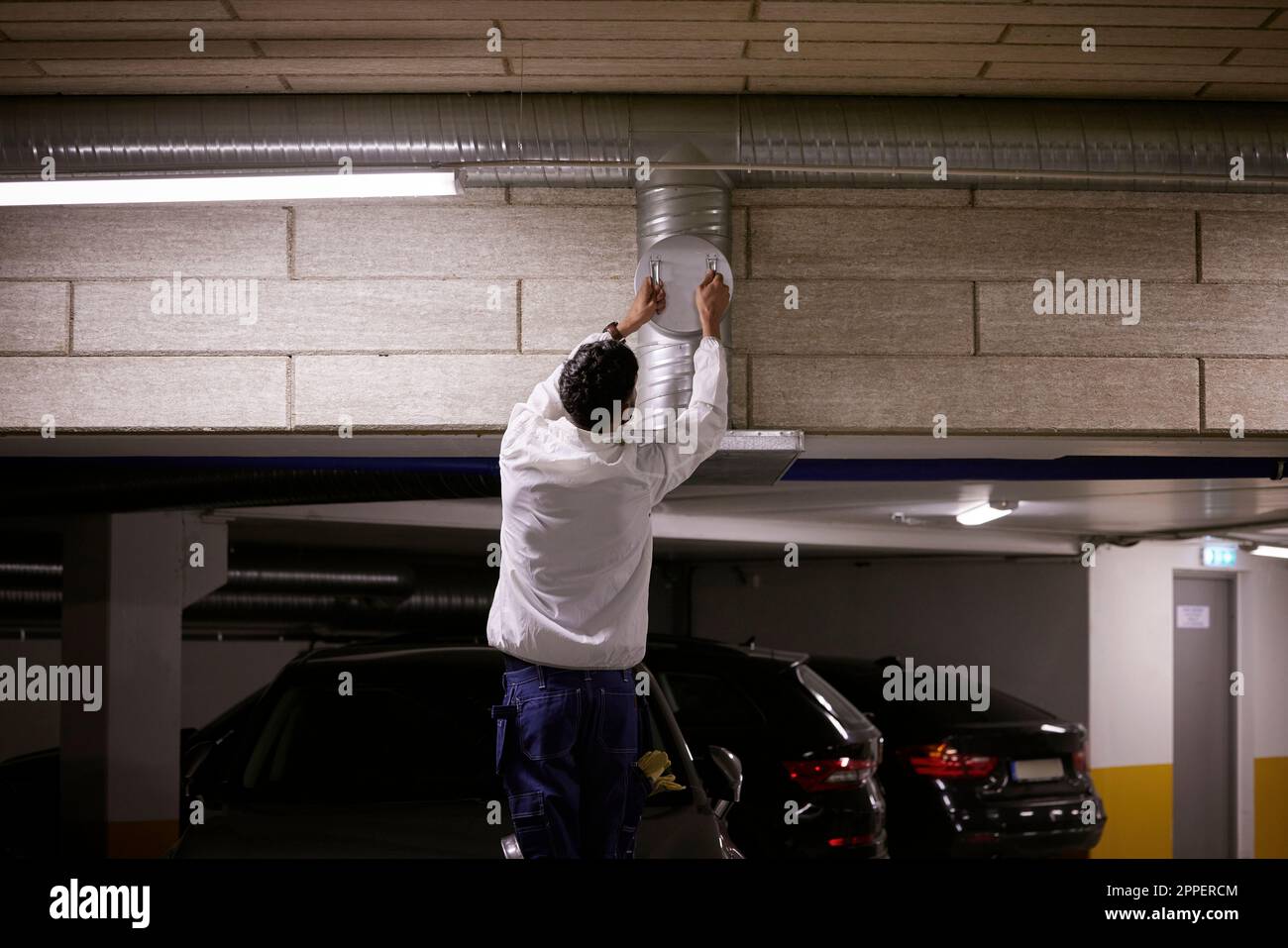 Rear view of man checking air duct Stock Photo - Alamy