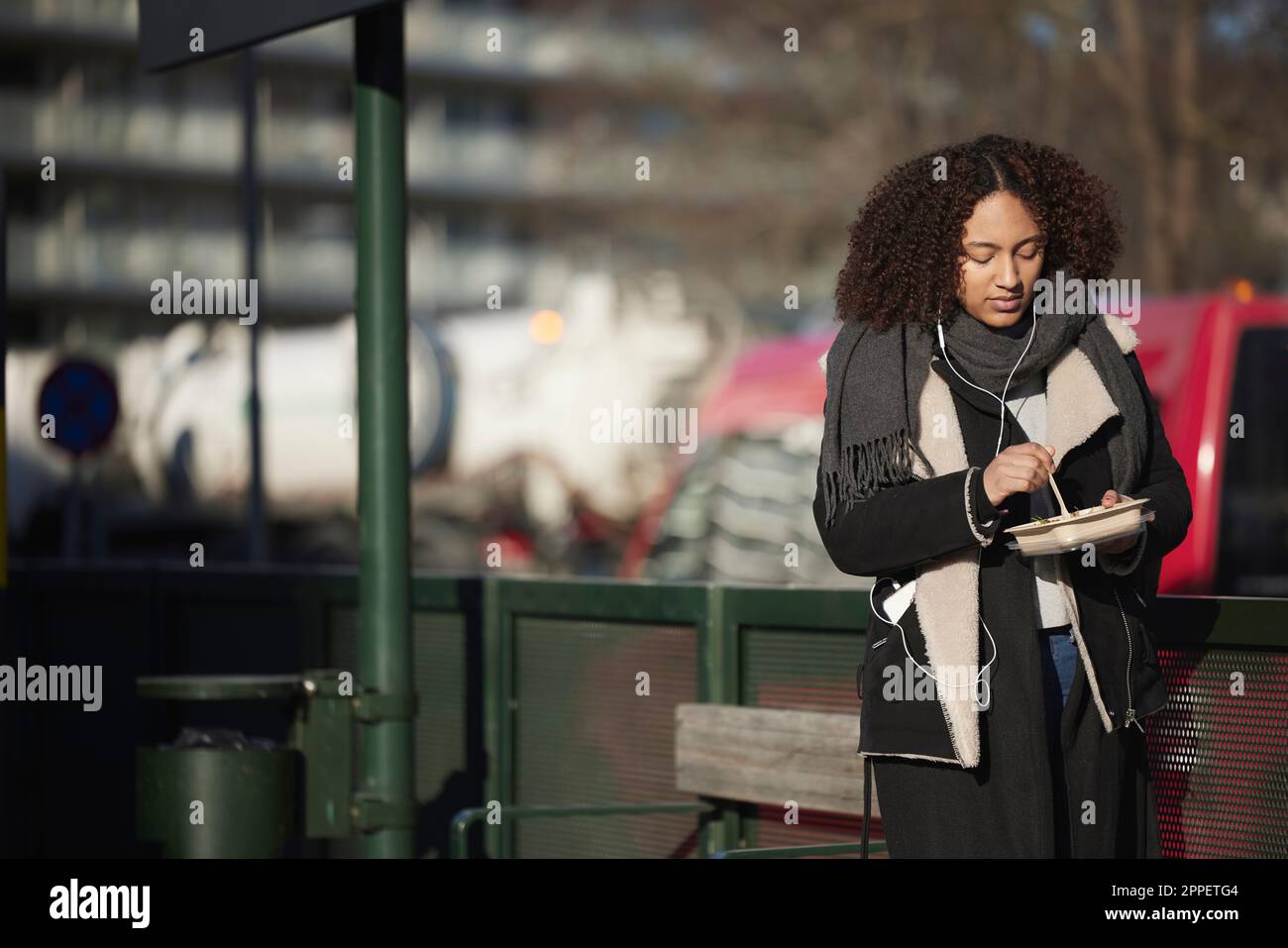 Woman eating at bus stop Stock Photo - Alamy