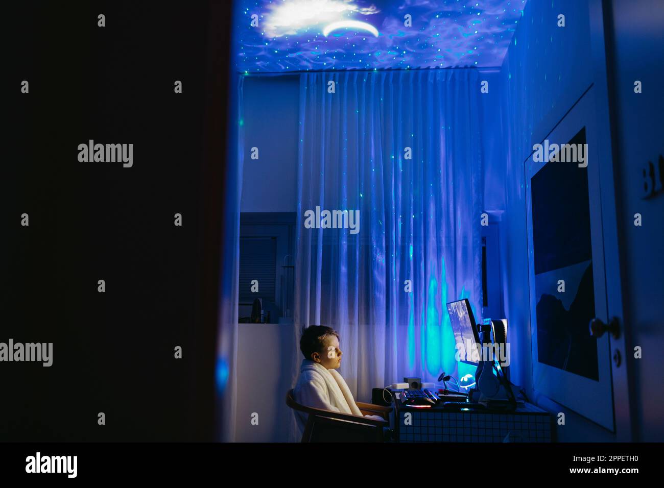 Boy at desk using computer at night Stock Photo - Alamy
