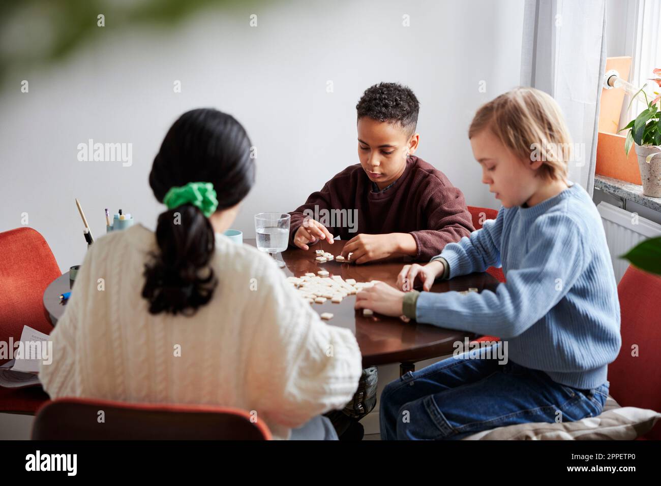 Girl and boys playing scrabble at dining table Stock Photo - Alamy