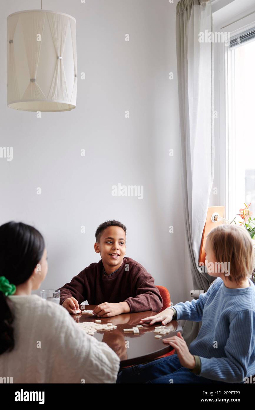 Girl and boys playing scrabble at dining table Stock Photo - Alamy