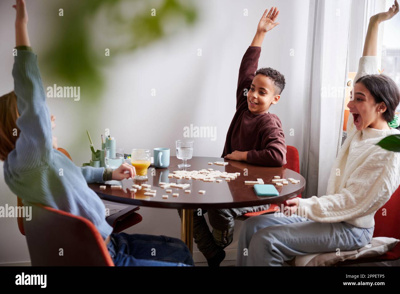 Girl and boys playing scrabble at dining table Stock Photo - Alamy