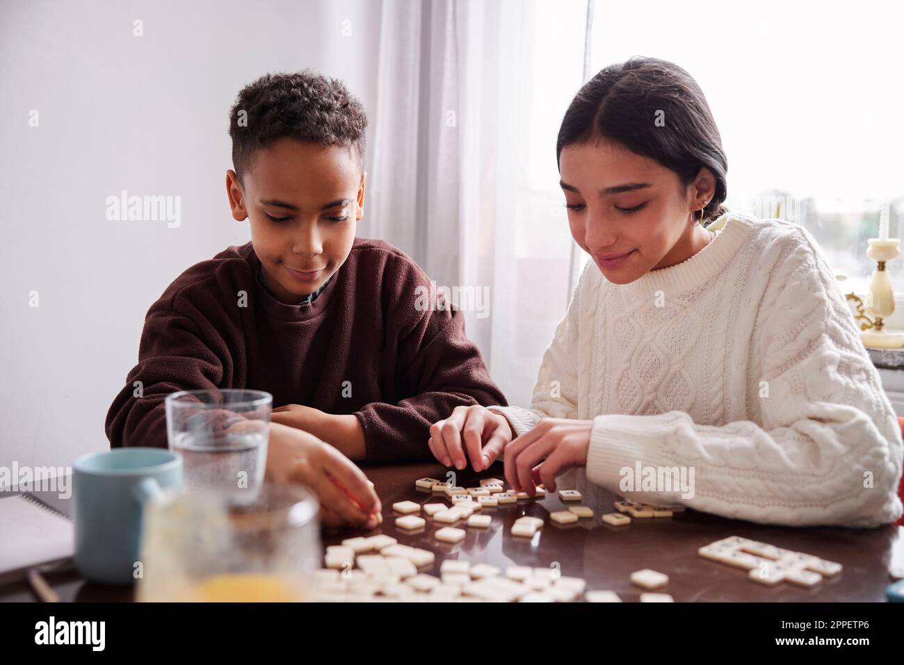 Girl and boy playing scrabble at dining table Stock Photo - Alamy