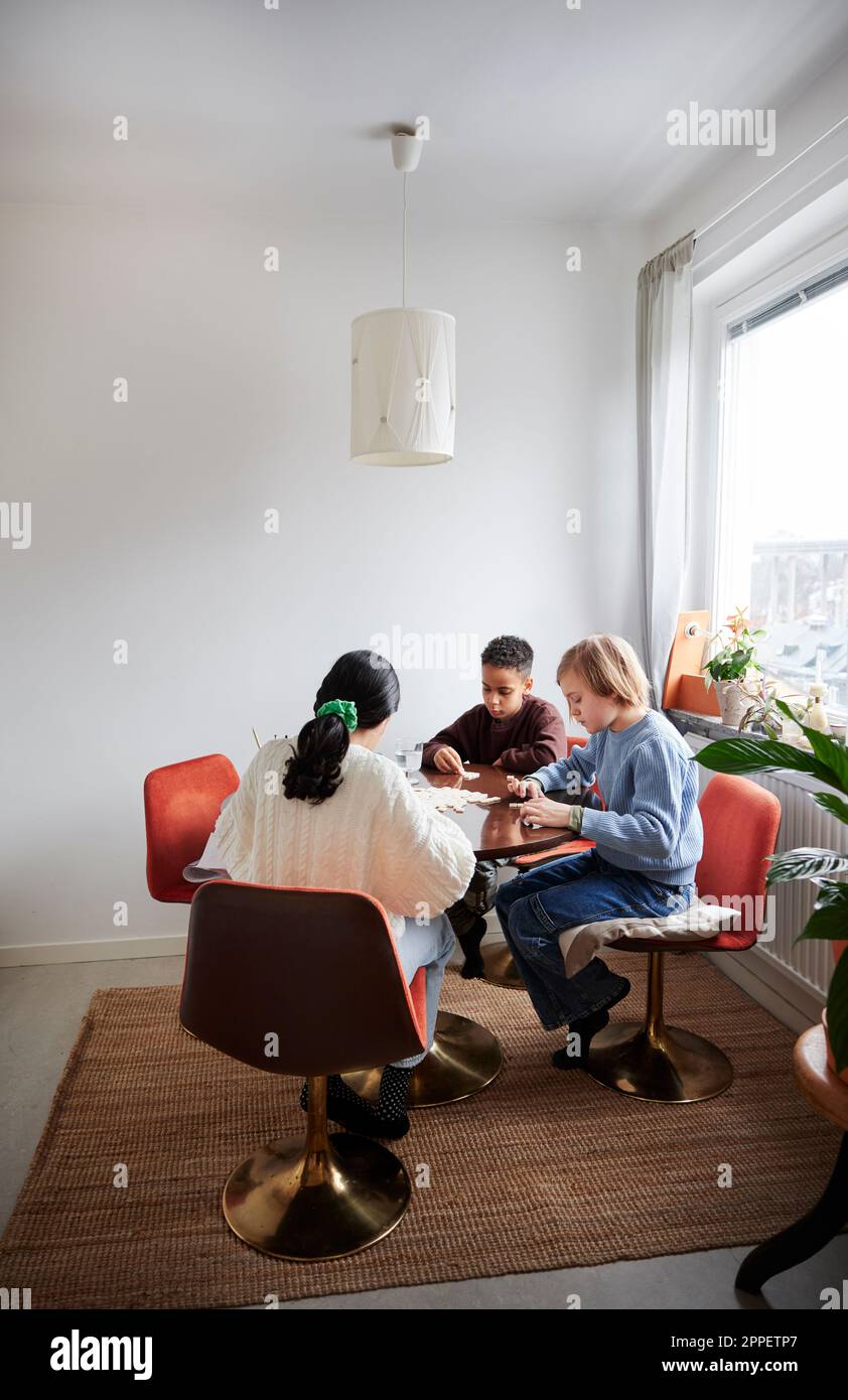 Girl and boys playing scrabble at dining table Stock Photo - Alamy