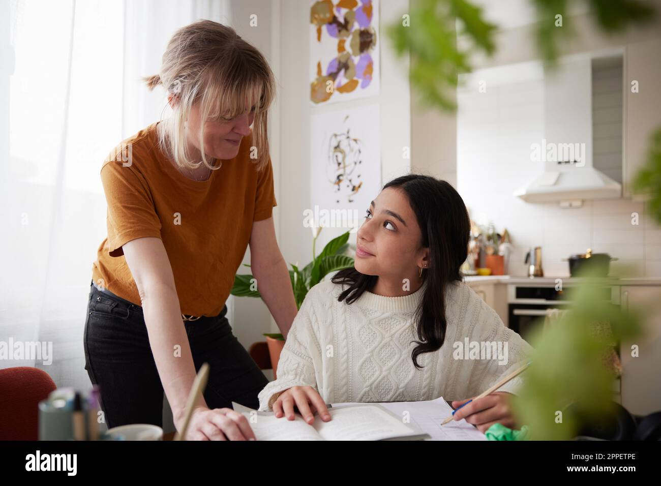 Mother assisting to girl doing homework Stock Photo - Alamy